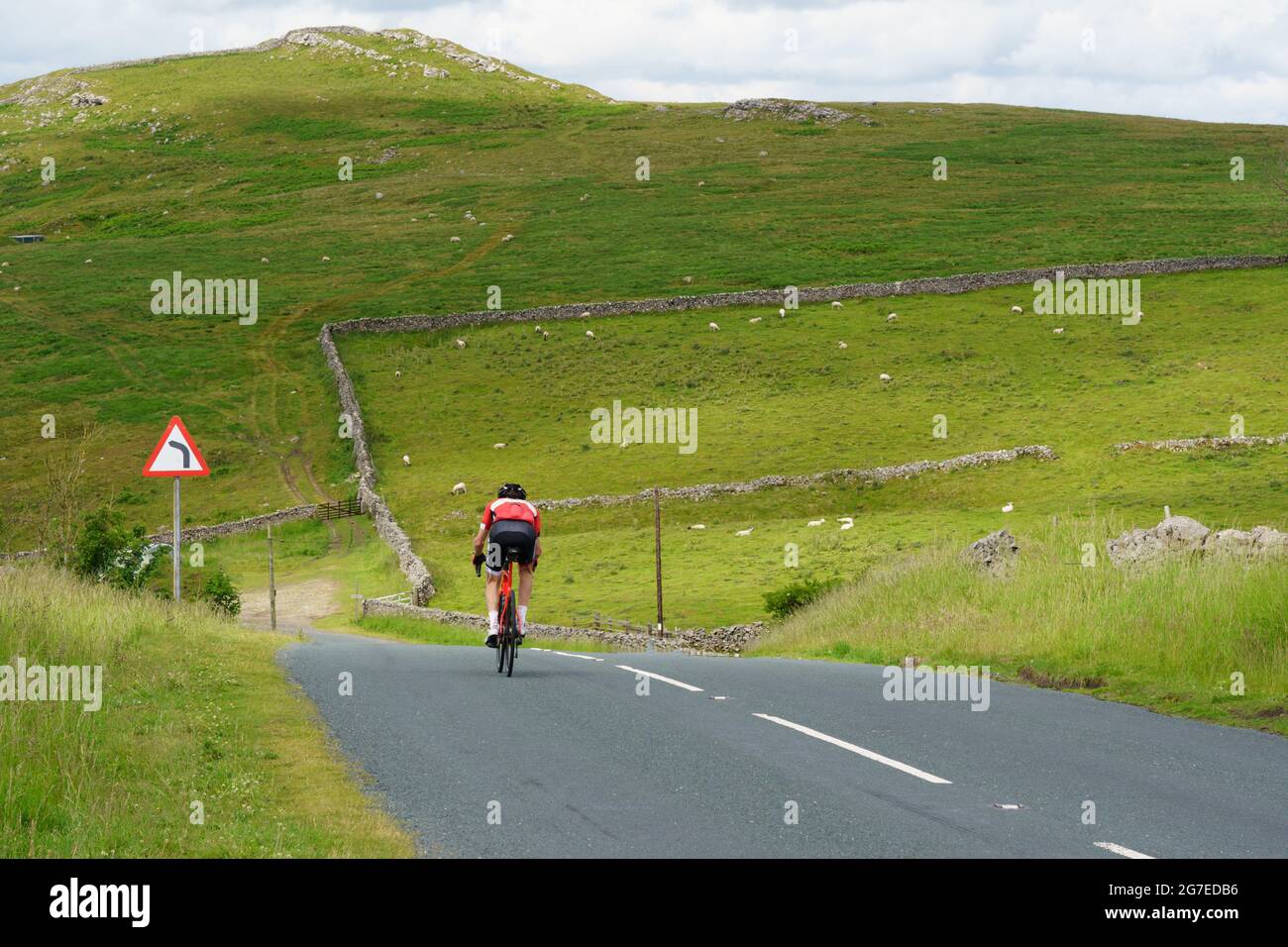 Cycling alone along a scenic country road, a man is facing a big hill ...
