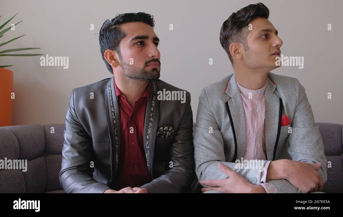View of two men wearing grey jackets sitting on the couch in the ...