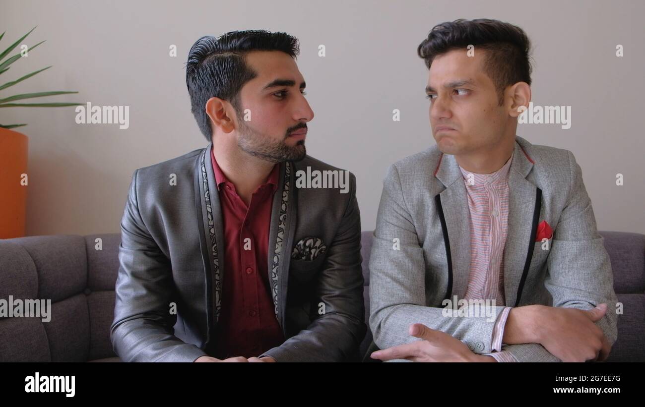 View of two men wearing grey jackets siting on the couch in the ...