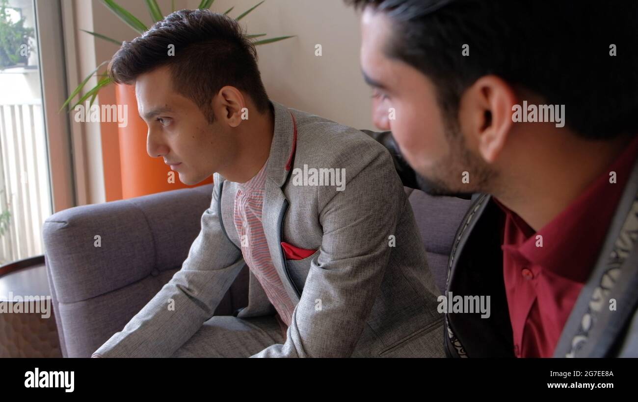 View of two men wearing grey jackets sitting on the couch in the ...