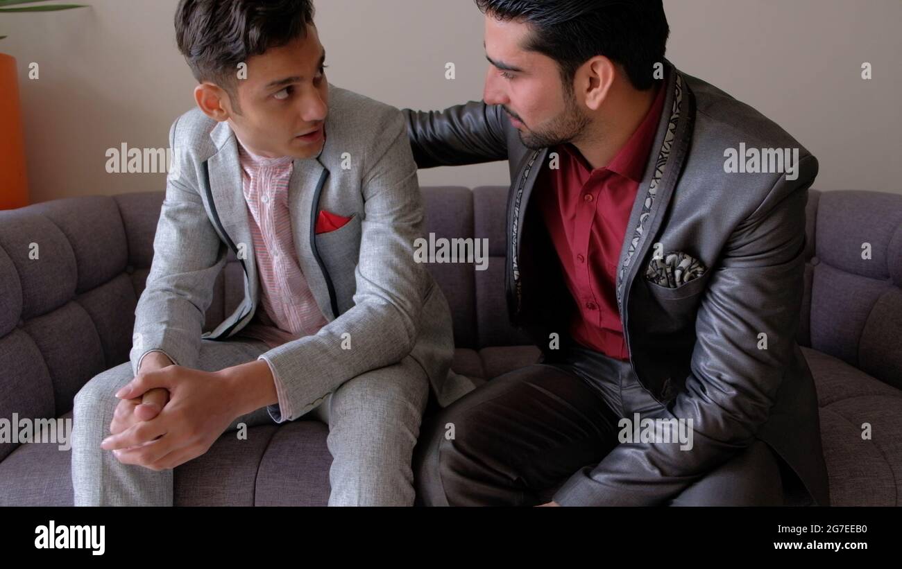 View of two men wearing grey jackets sitting on the couch in the ...