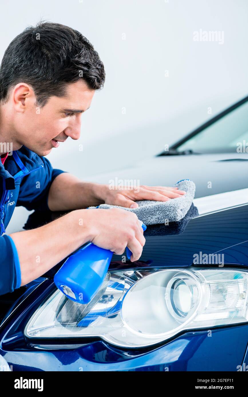 Man cleaning his luxury blue sedan car with a sponge and spray bottle ...