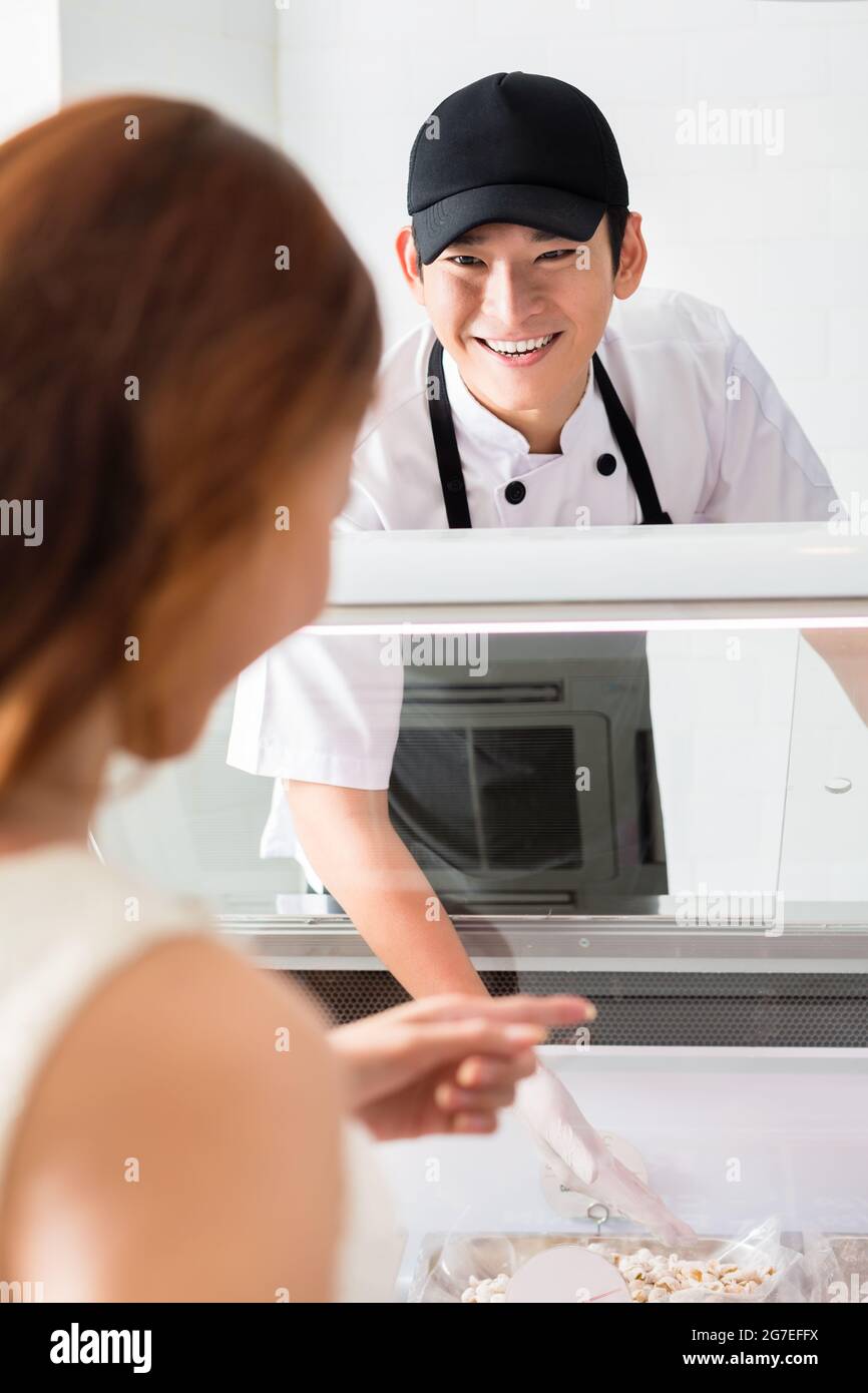 Smiling helpful assistant serving a female customer to food in a ...