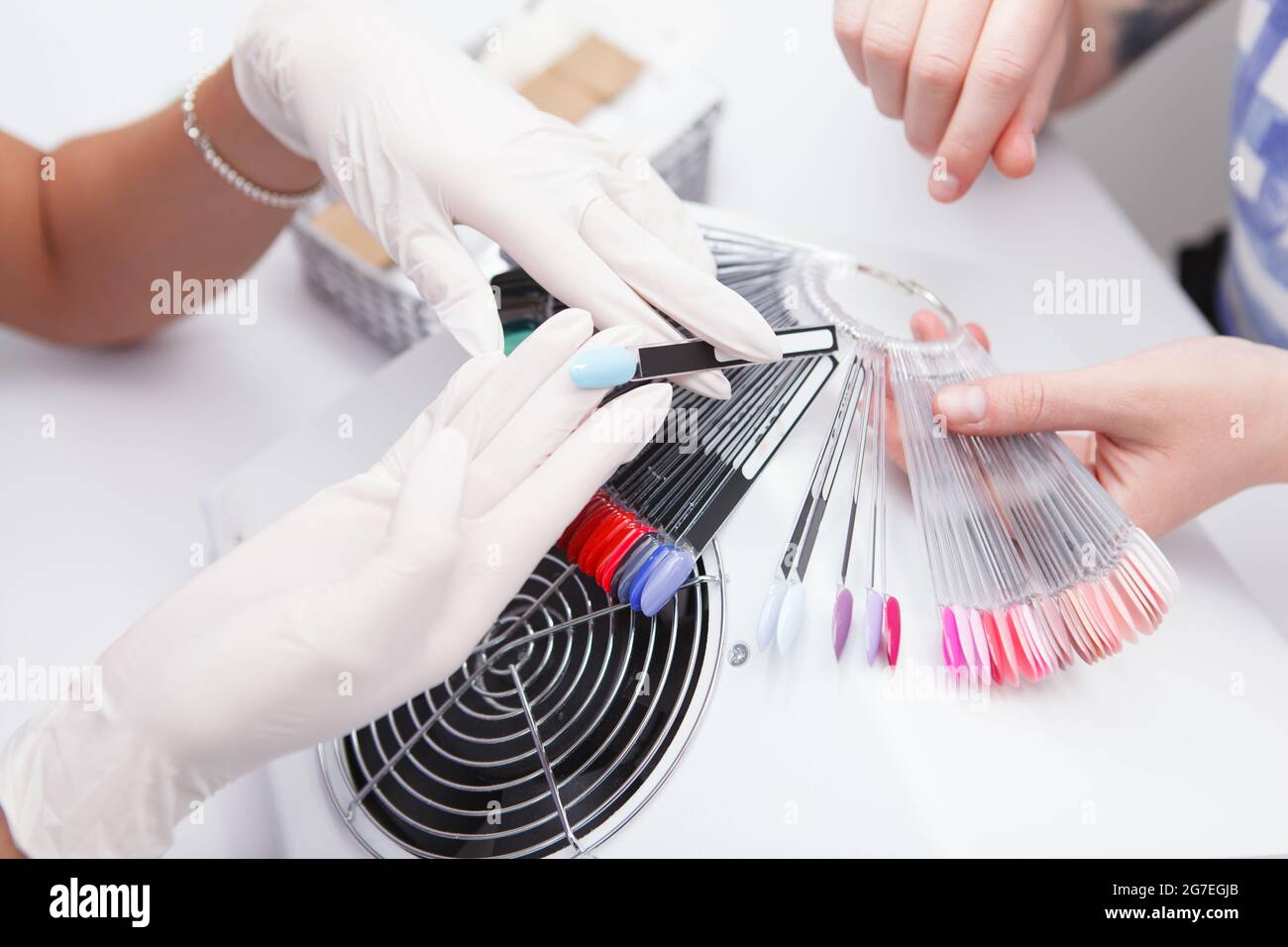 Close up of manicurist helping client choose nail color from nail ...