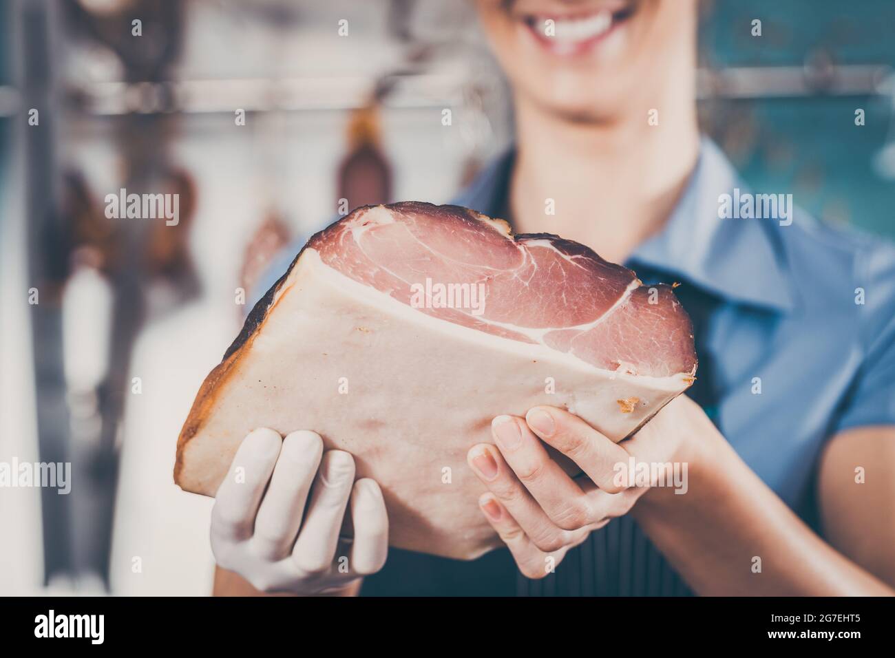 Young woman or female butcher with raw ham in butchers shop selling ...