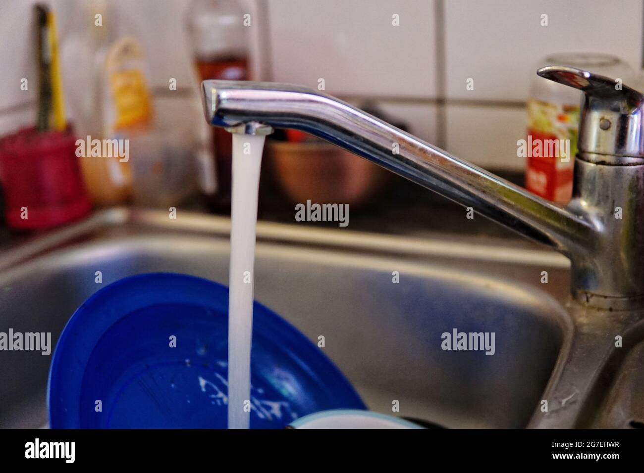 Closeup shot of a kitchen sink with running water on the plates and ...