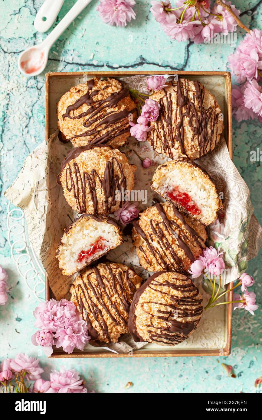 Chocolate drizzled coconut macaroons on a tray. One of them has been ...