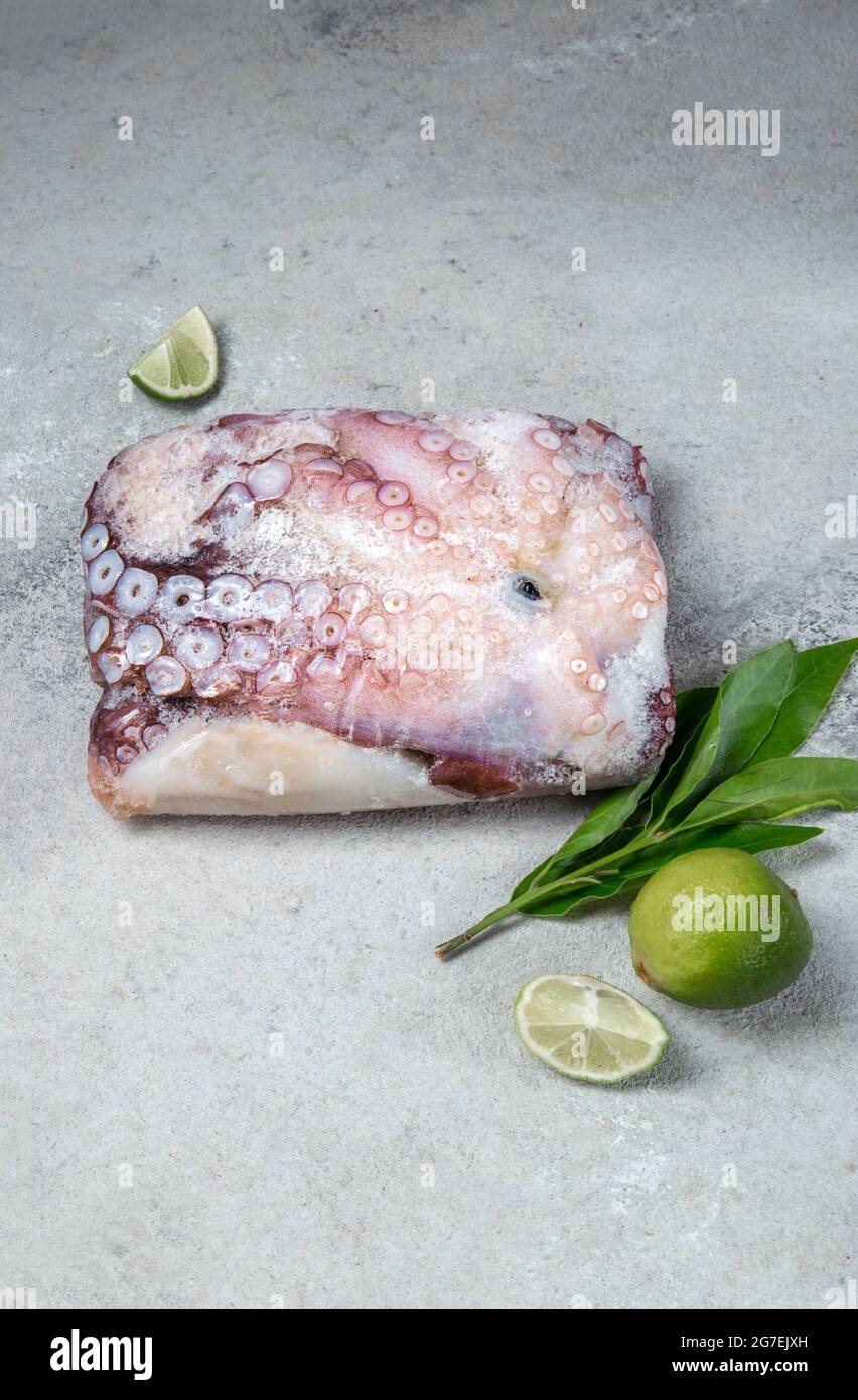 Frozen whole octopus with ingredients for cooking - bay leaf and lime ...