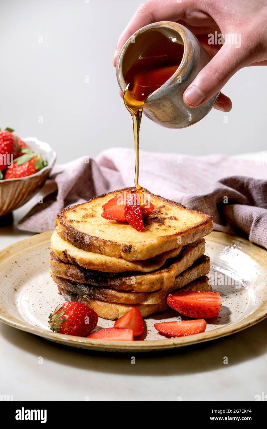 Male hand pouring maple syrup from ceramic jug on stockpile of french ...