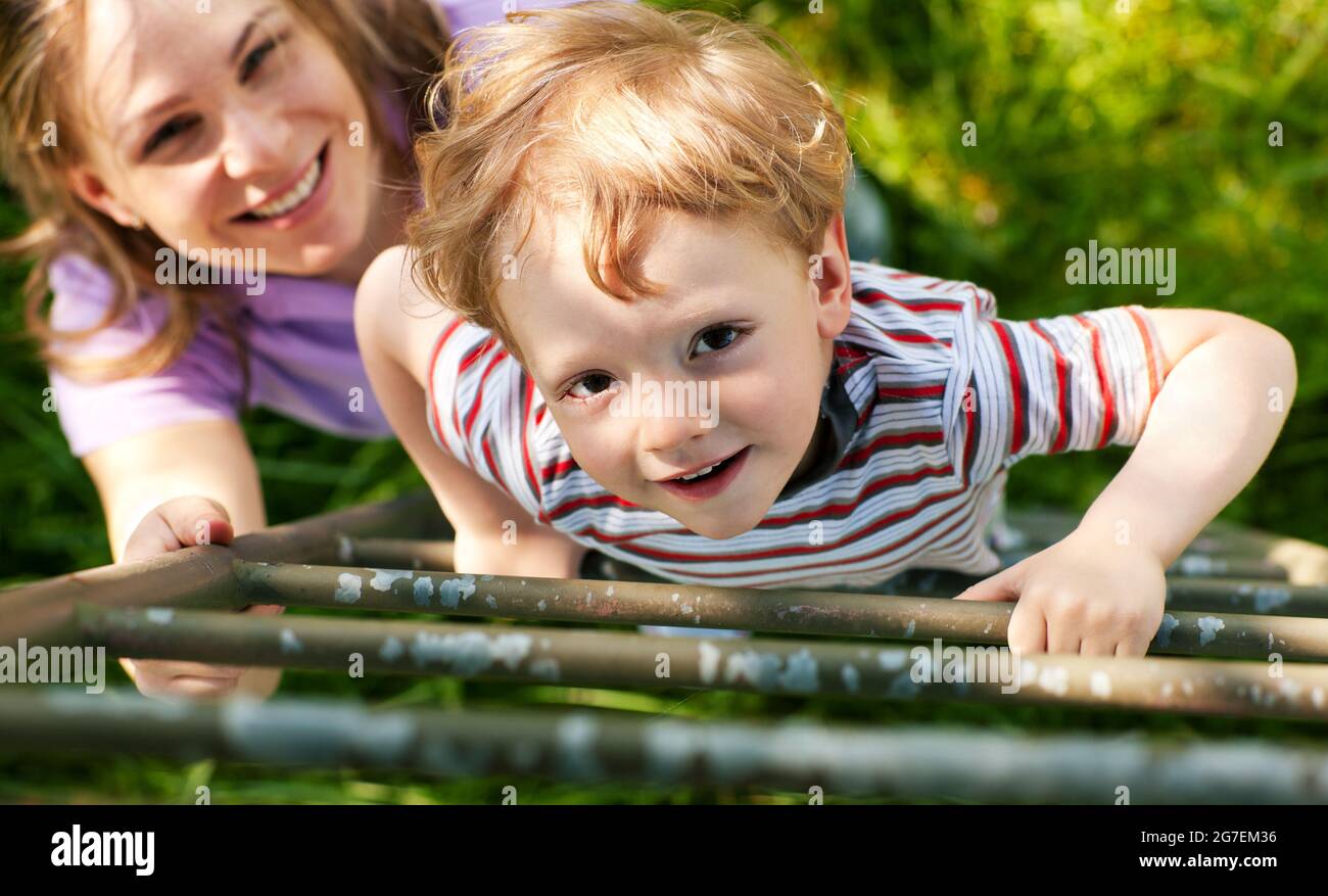Little boy and his mother climbing up a ladder, they want to reach ...