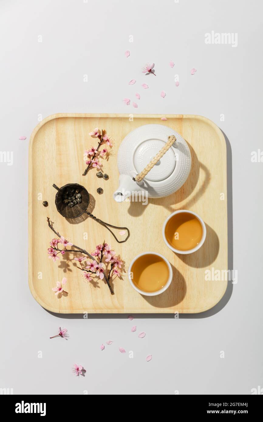 Tea concept, two white cups of tea, teapot, tea strainer and spring ...