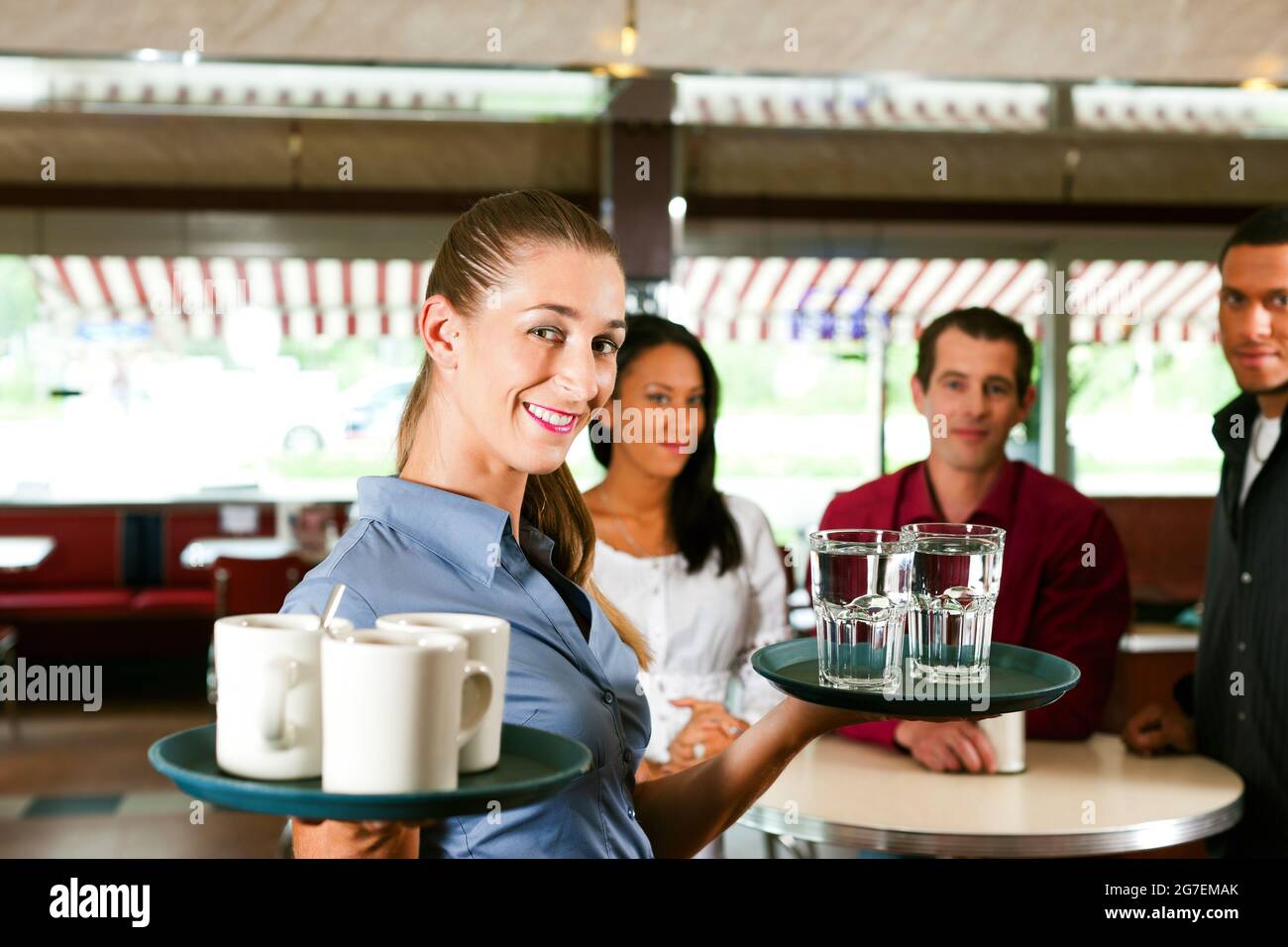 Woman as waitress in a bar or restaurant with coffee mugs; in the ...