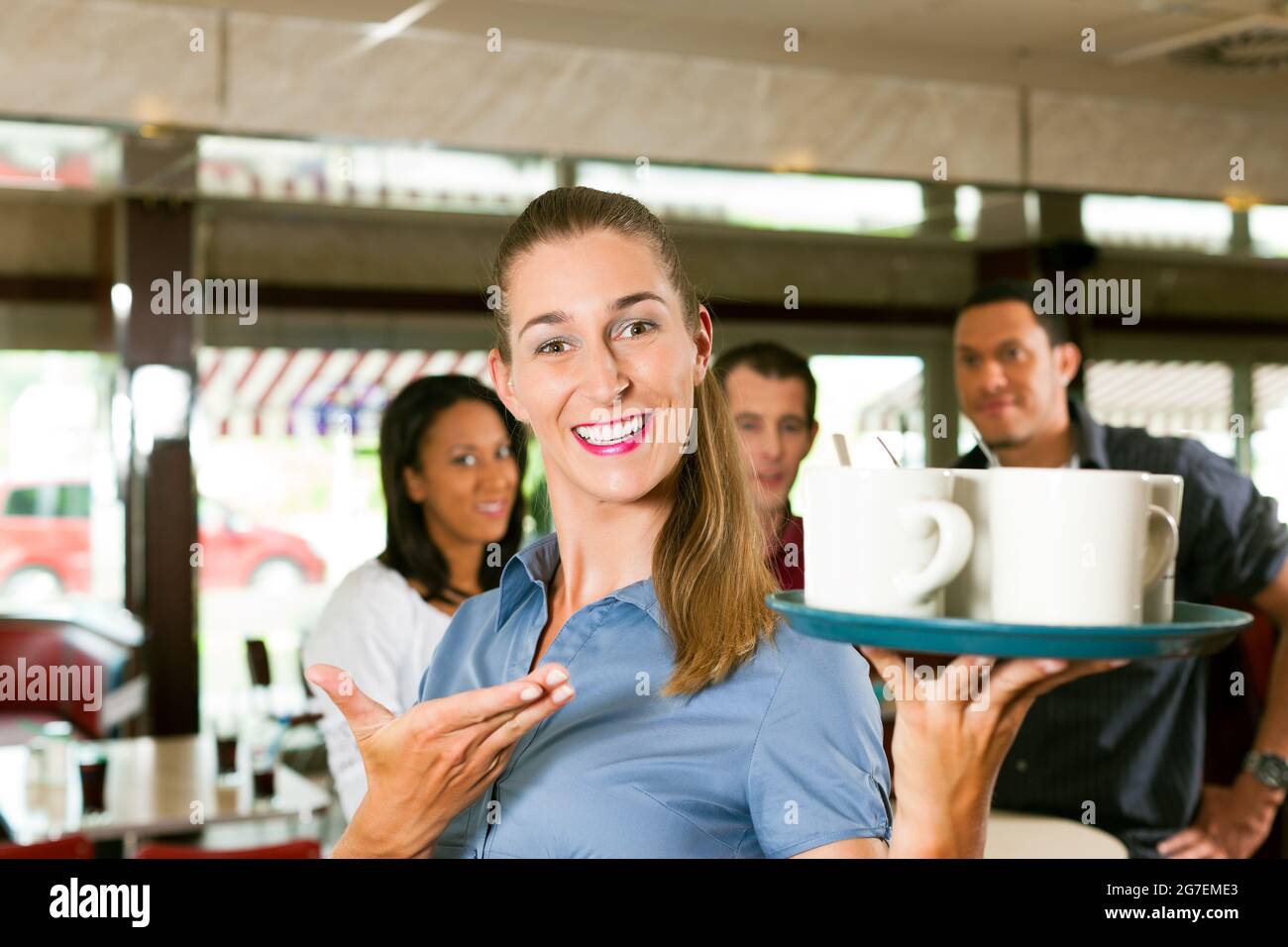 Woman as waitress in a bar or restaurant with coffee mugs; in the ...