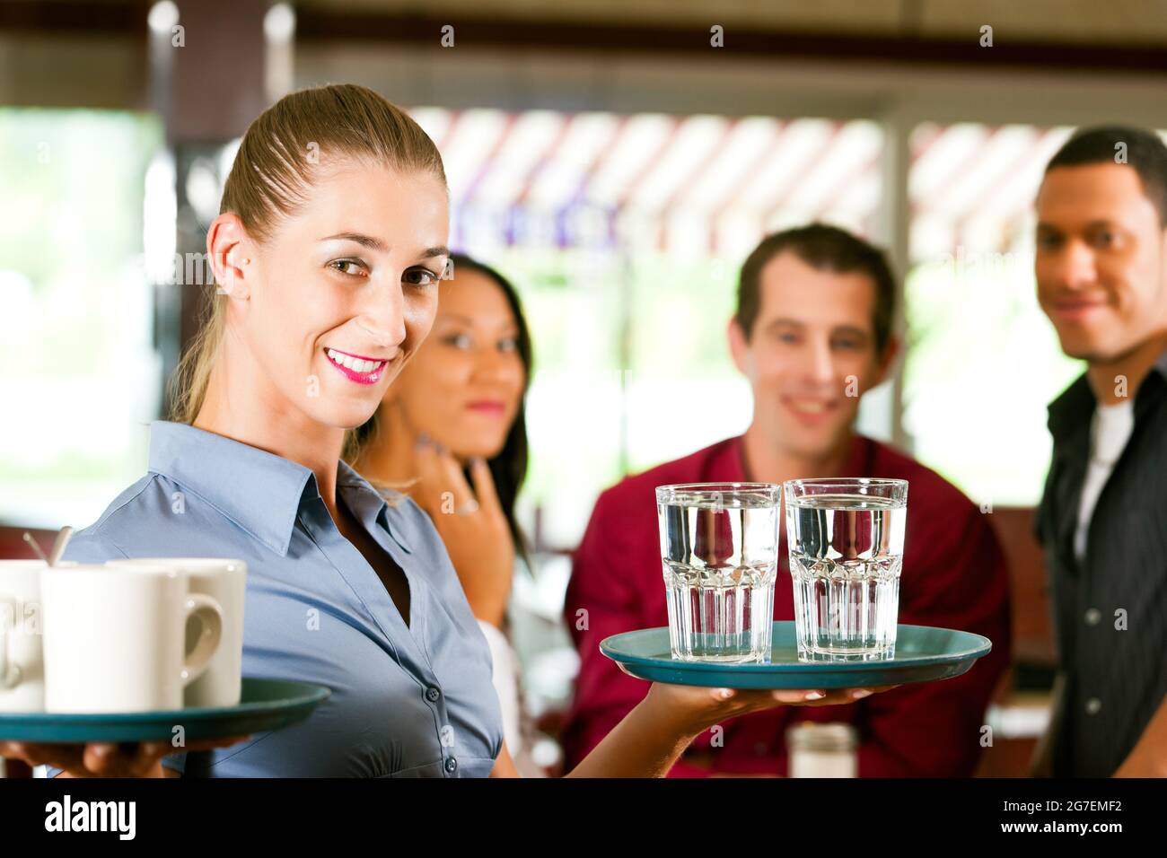 Woman as waitress in a bar or restaurant with coffee mugs; in the ...