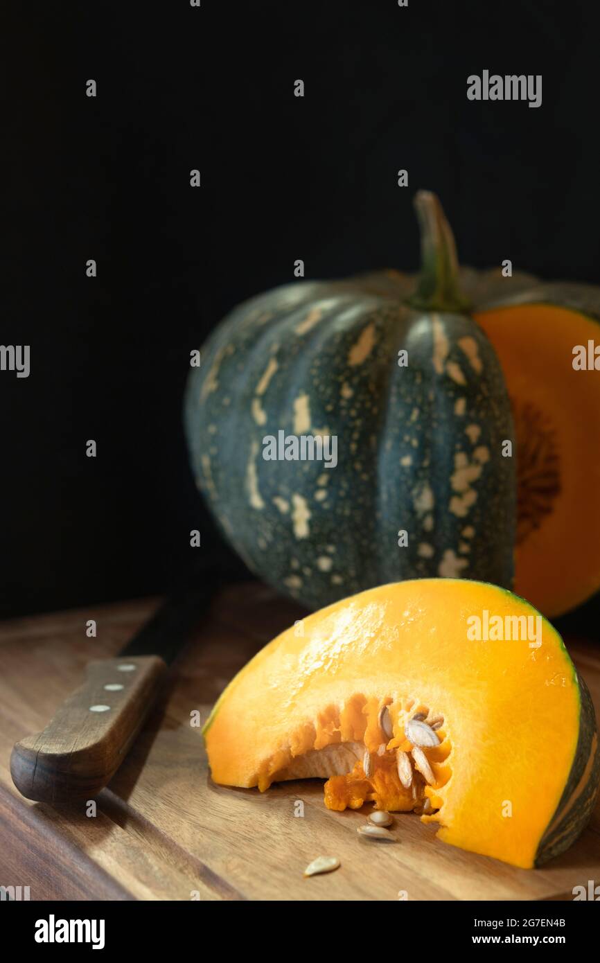 A pumpkin on a cuttting board with a slice cut Stock Photo - Alamy