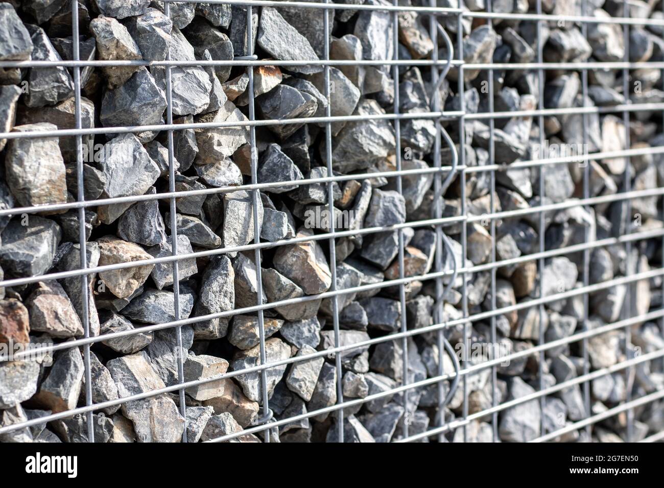 Small granite stones behind a metal mesh, design fence, garden concept ...