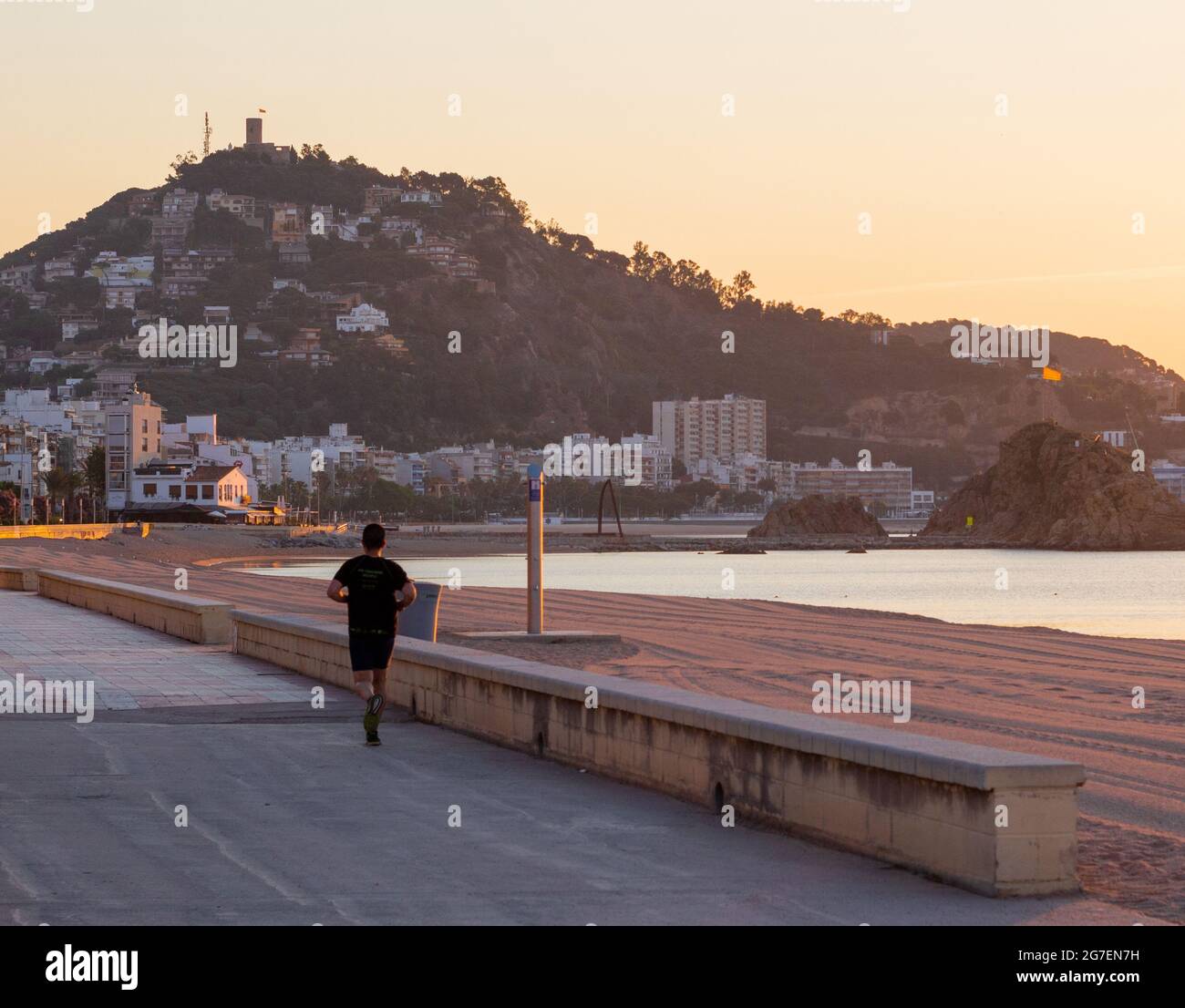 Back shot of a young man black outfit running beside the beach at ...