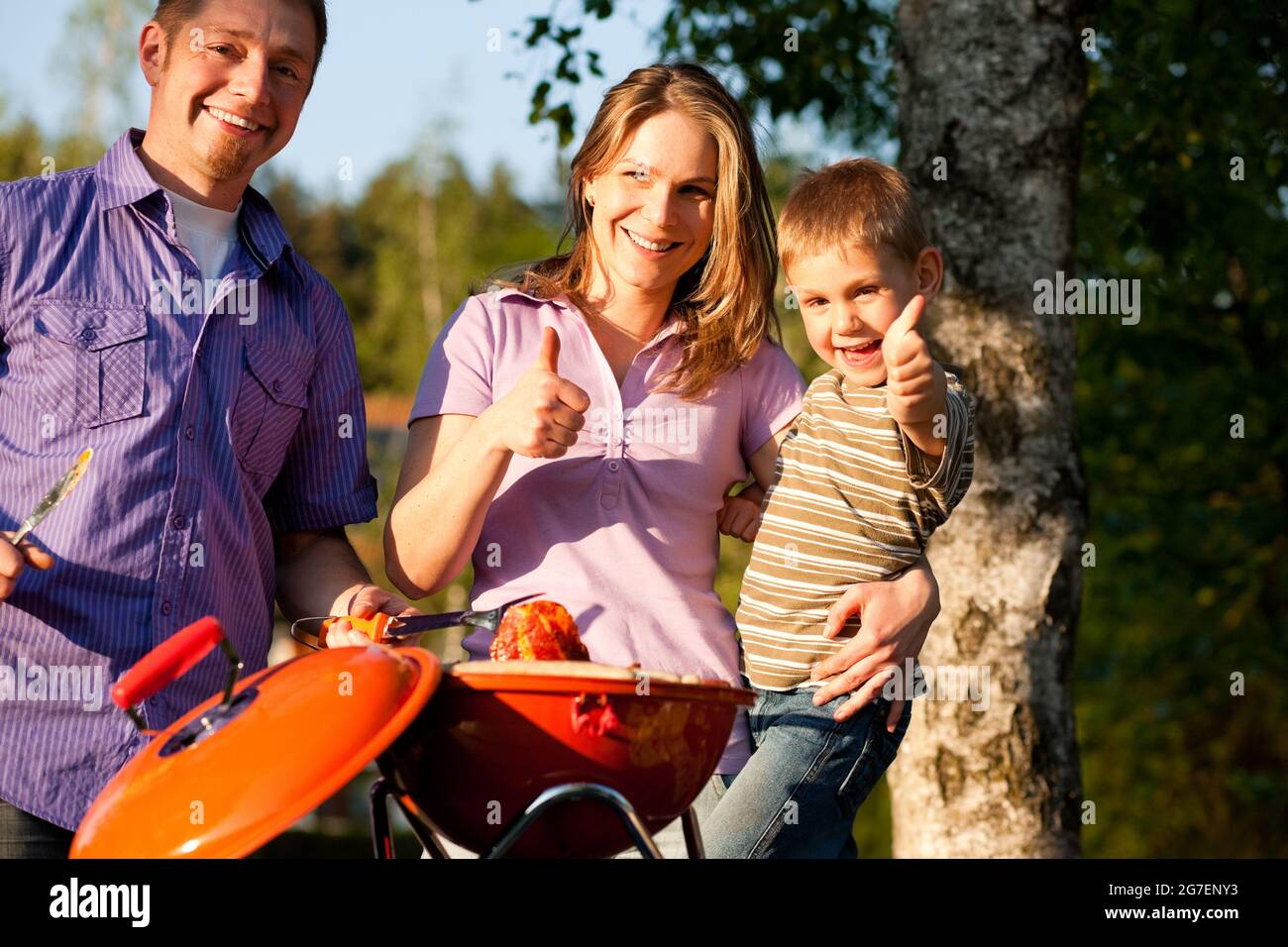 Family having a barbecue party, mother father and son standing around ...