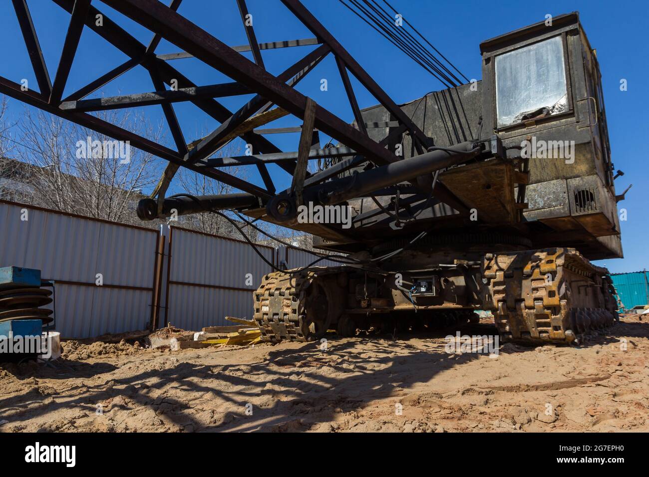 Old crawler crane at a construction site. Excavator tracks covered in ...