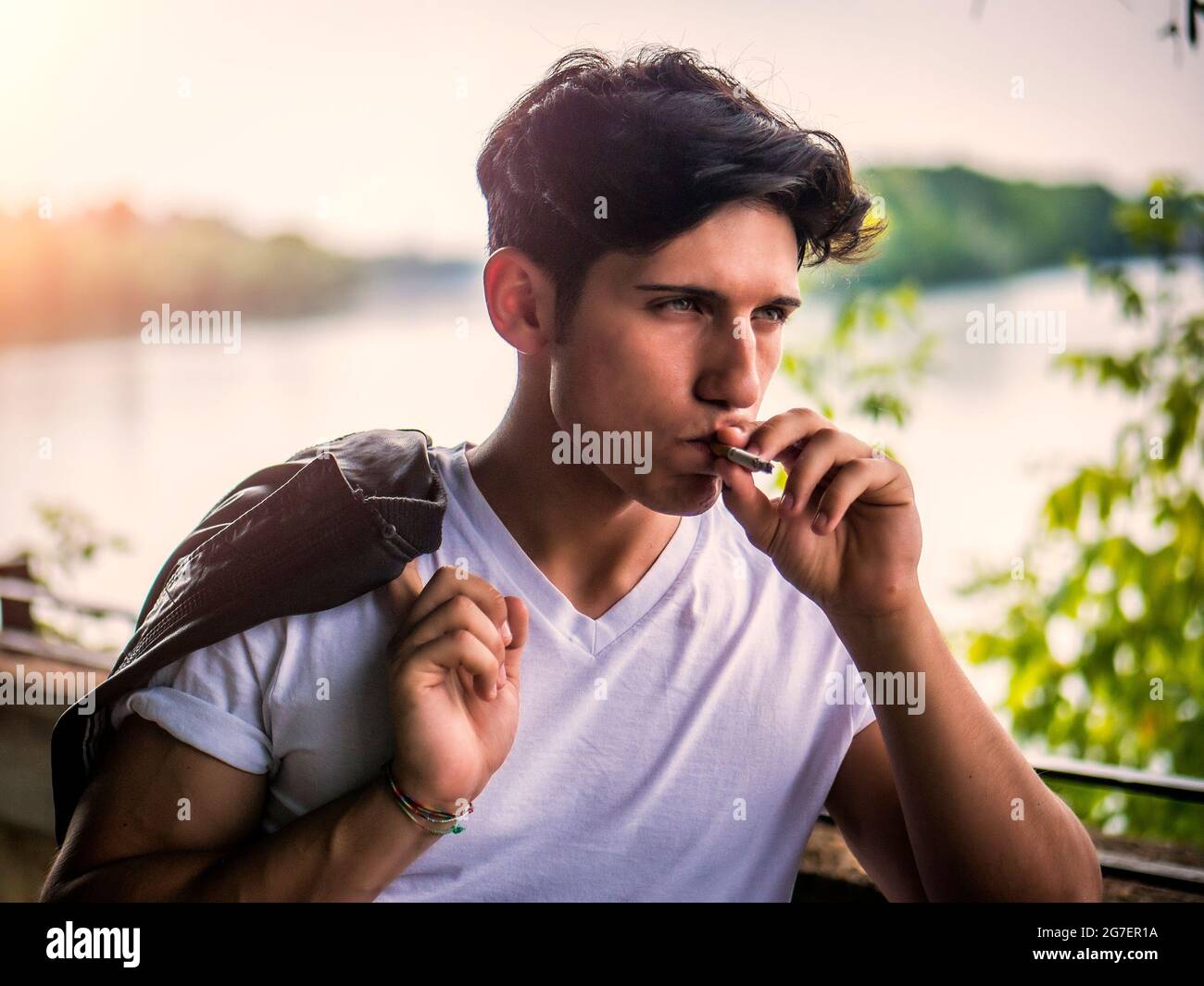 Handsome stylish young man smoking cigarette outside Stock Photo - Alamy