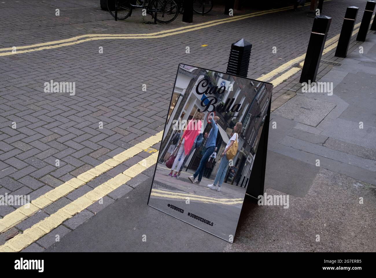 Women shoppers walk along Neal Street, passing-by a mirrored sign for ...
