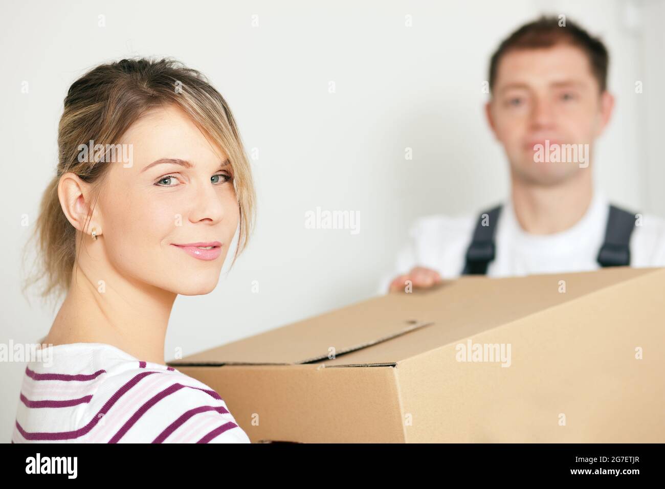 Woman moving in her new house, she is getting friendly help by a mover ...
