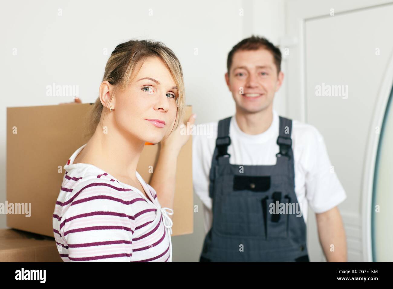 Woman moving in her new house, she is getting friendly help by a mover ...