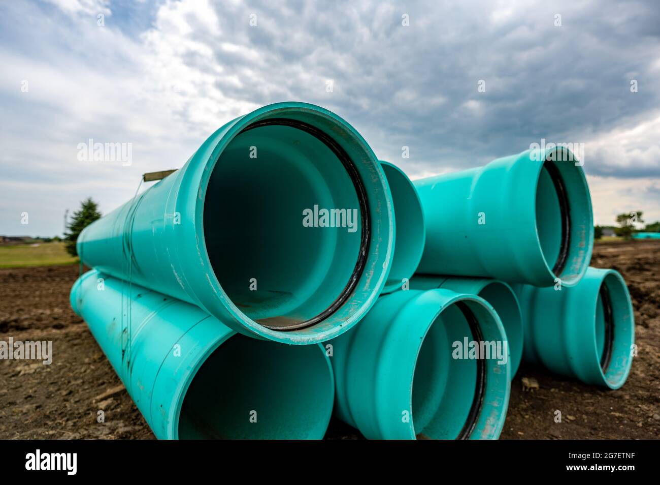 Stacked water main pipe with bell fitting next to an exposed trench for ...