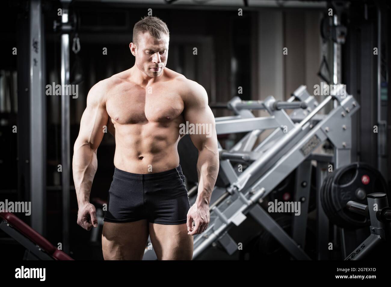 Strong man doing bodybuilding in gym standing in front of a dumbbell ...