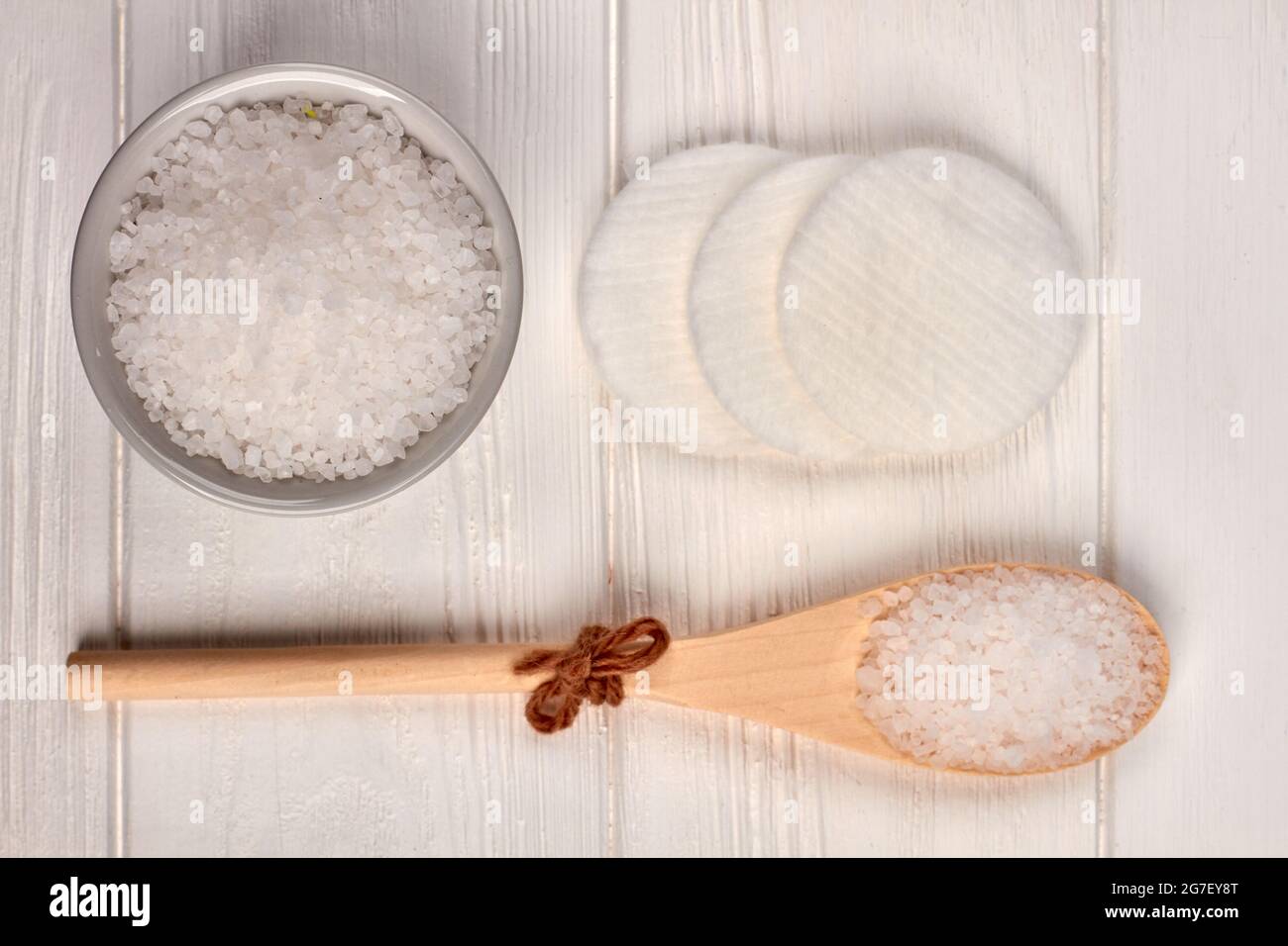 Wooden spoon with salt and cotton pads on white desk Stock Photo - Alamy