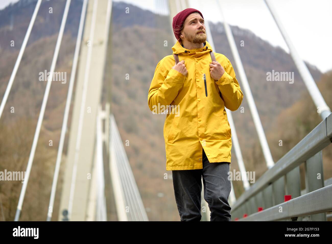 Man in yellow coat walking alone on pedestrian pathway on bridge in an ...