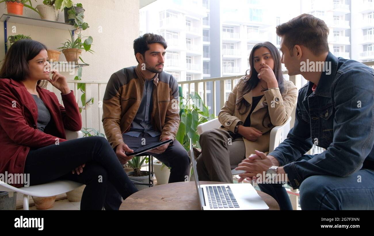 Group of Indian friends seated in their house balcony terrace talking ...