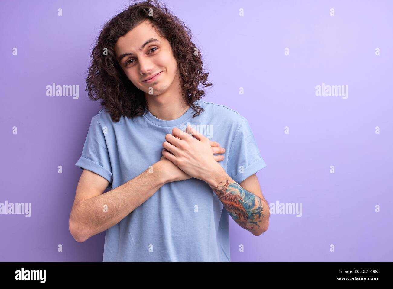 Open-minded guy with curly hair keep hands on chest, male is grateful ...