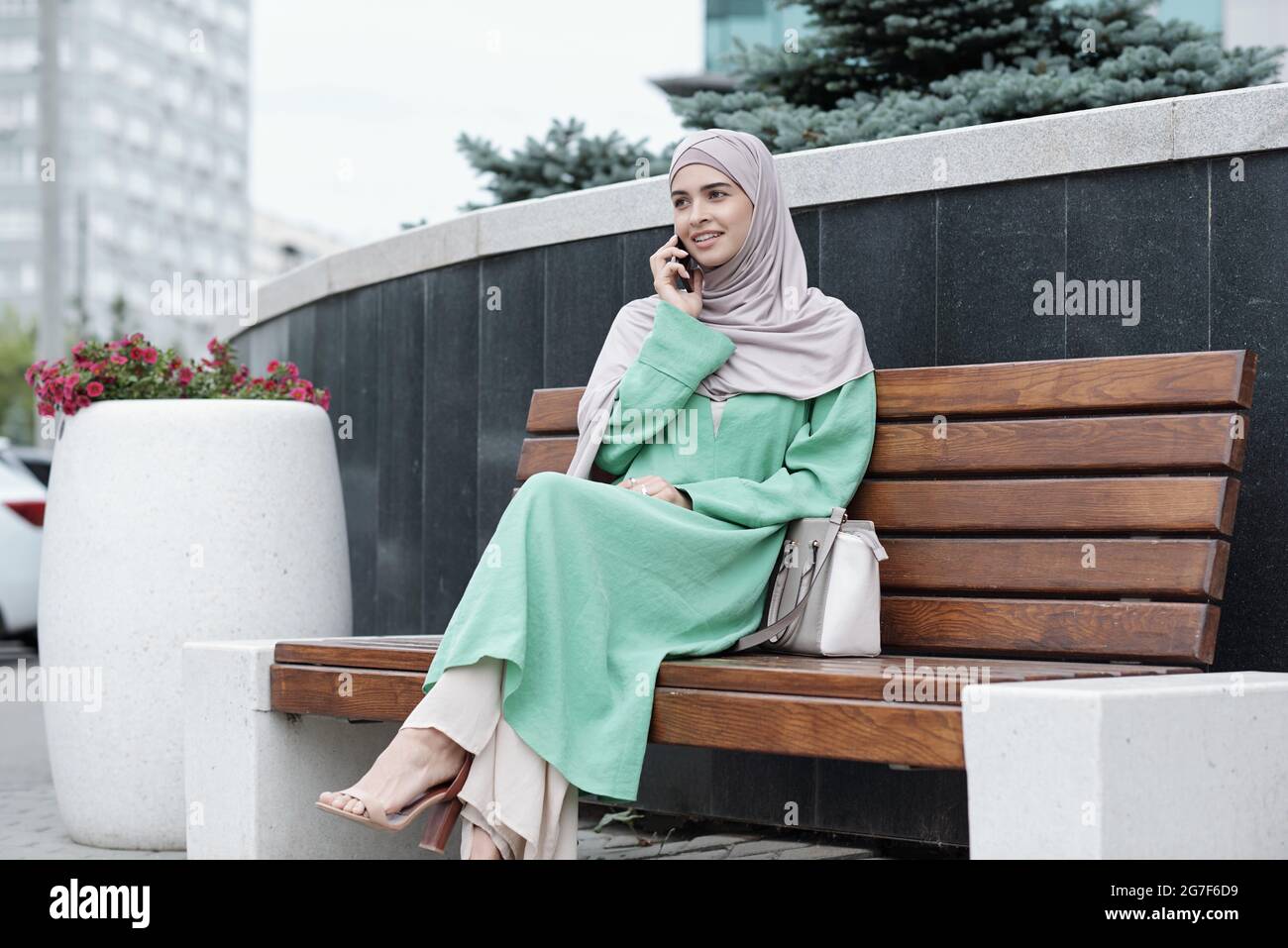 Smiling stylish young Muslim businesswoman in long green dress and ...