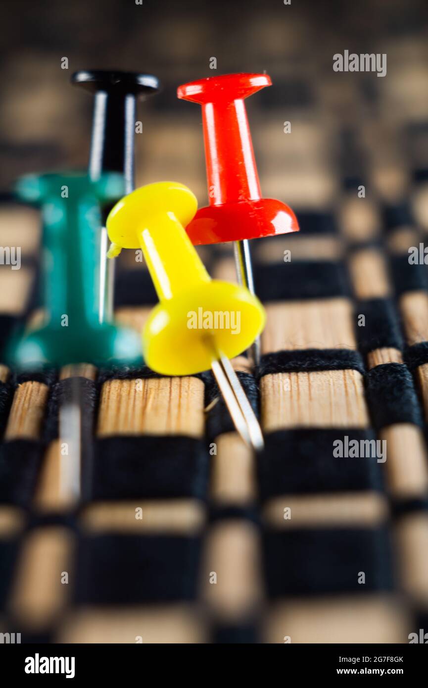Close-up photo of a set of multi-colored push pins fixed in a table ...
