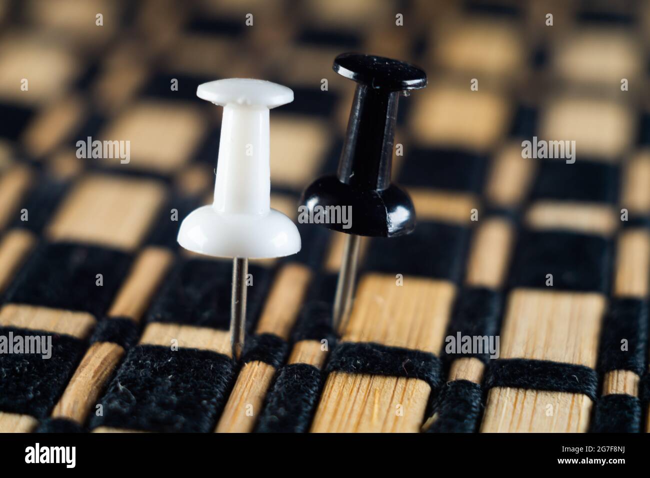 Pair of black and white pushpins on a patterned surface Stock Photo - Alamy