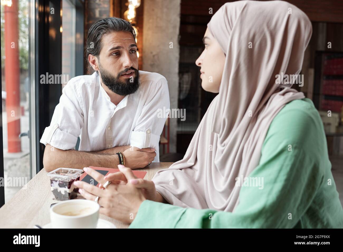 Handsome young Muslim man talking to girl while they having breakfast ...