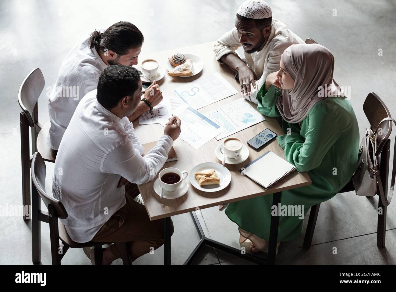 Group of young Muslim colleagues sitting at table and brainstorming ...