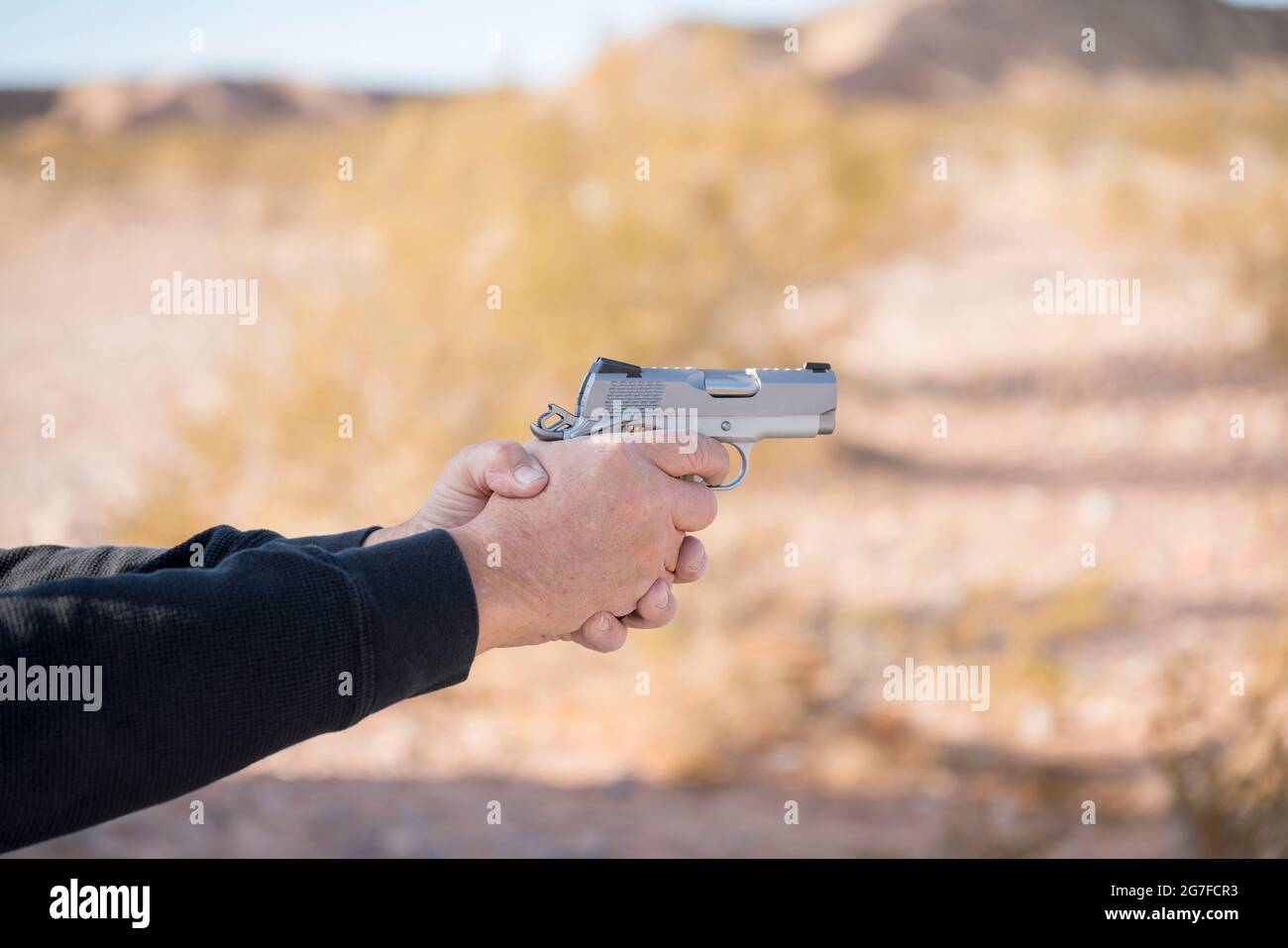 Two hands gripping on a small silver gun with a blurry background Stock ...
