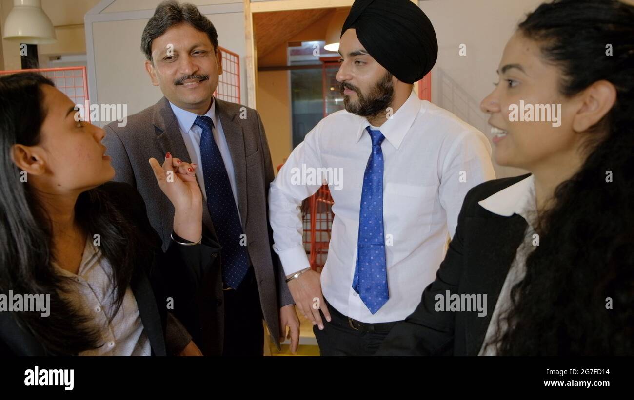 Group of Indian workers talking before a business meeting in office ...
