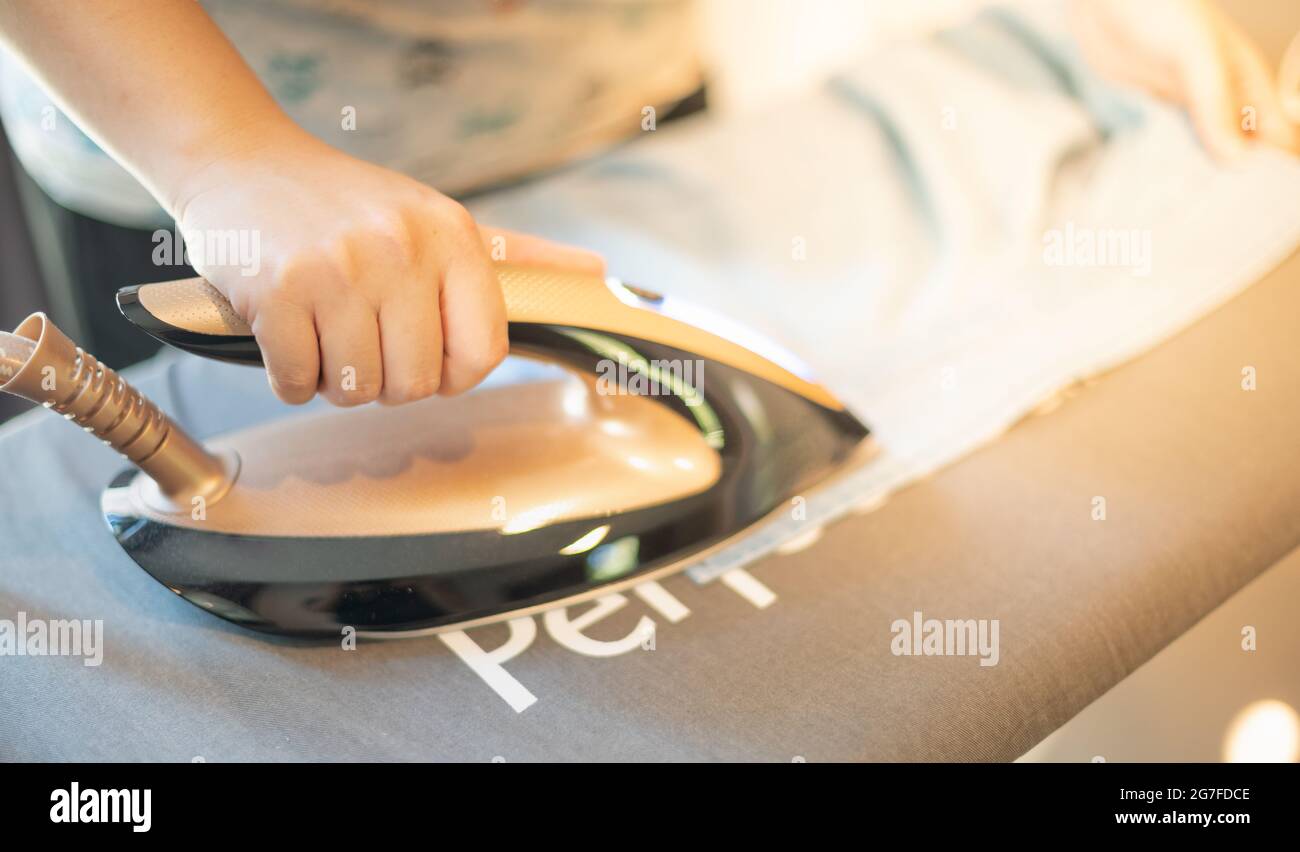 Female hand ironing clothes on iron board at home in the laundry day ...
