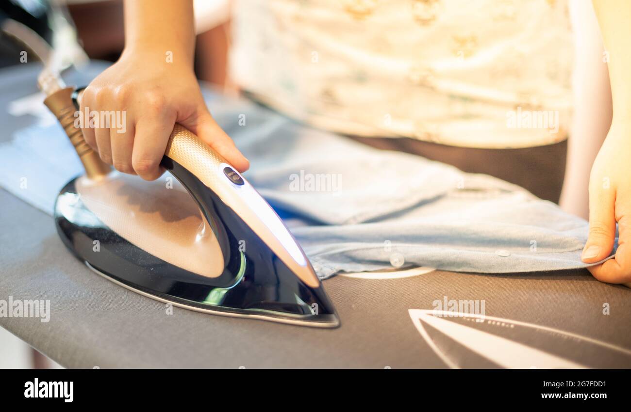 Female hand ironing clothes on iron board at home in the laundry day ...