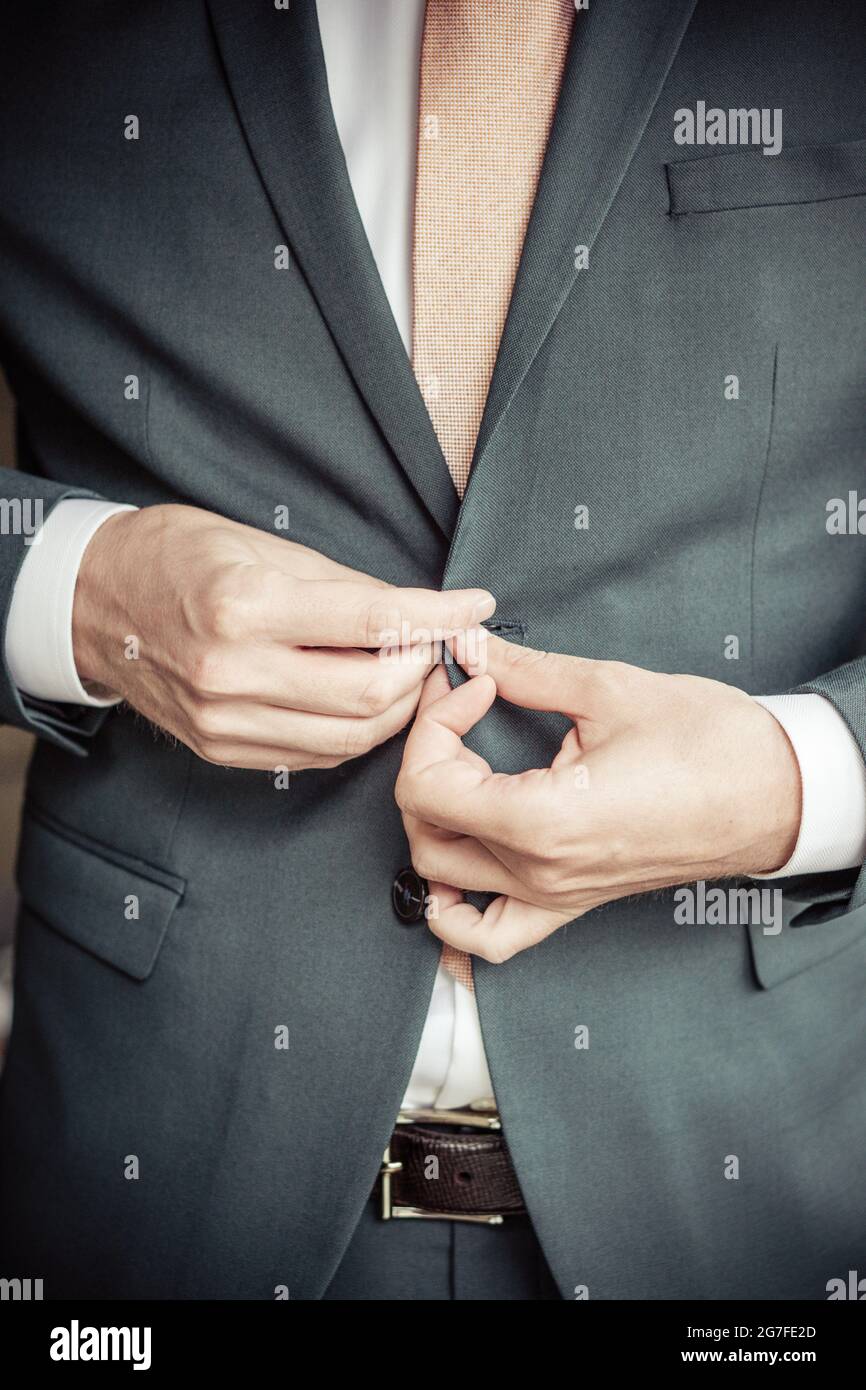 Vertical shot of a male buttoning his grey coat Stock Photo - Alamy