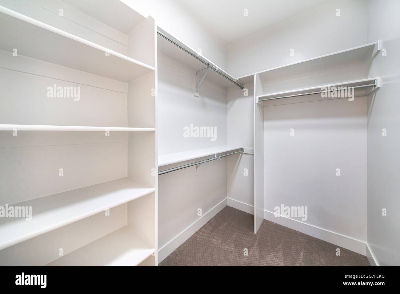 Small walk in closet with white shelvings and rods Stock Photo - Alamy