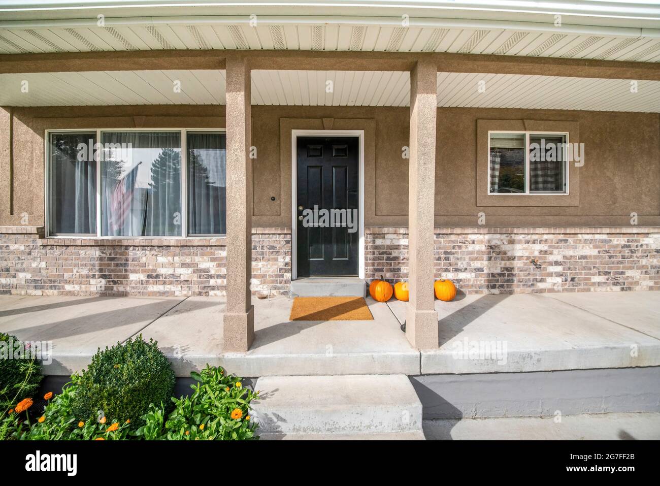 Front door exterior with half brick walls and two column posts in the ...