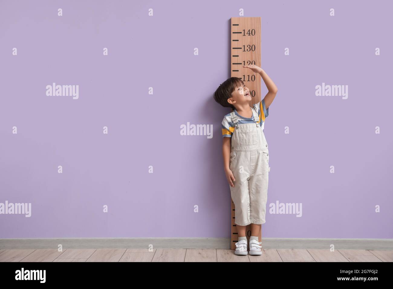 Little boy measuring height near color wall Stock Photo - Alamy