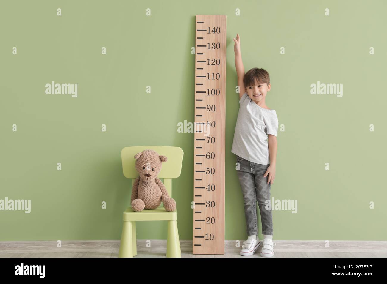 Little boy measuring height near color wall Stock Photo - Alamy