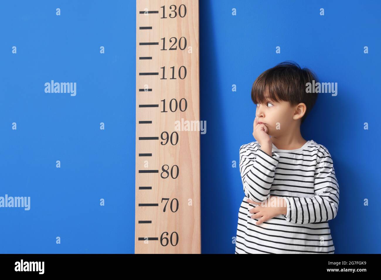 Little boy measuring height near color wall Stock Photo - Alamy