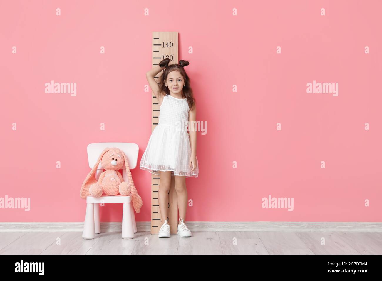 Little girl measuring height near color wall Stock Photo - Alamy