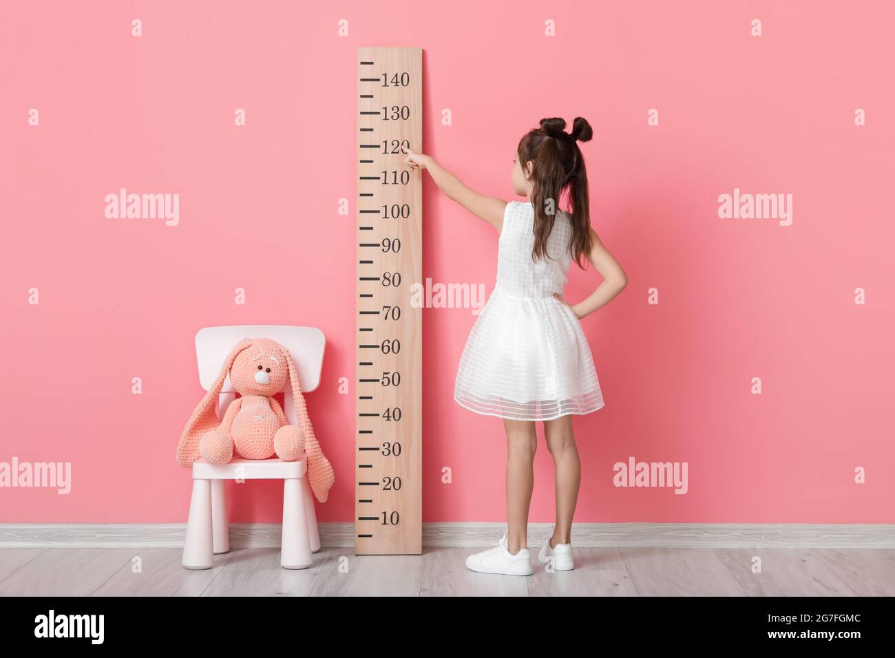 Little girl measuring height near color wall Stock Photo - Alamy